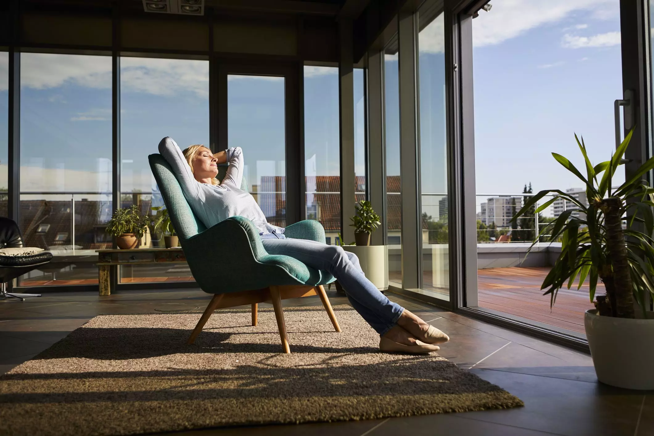 frou sunbathing yn 'e wenkeamer fan har hûs sittend op' e bank