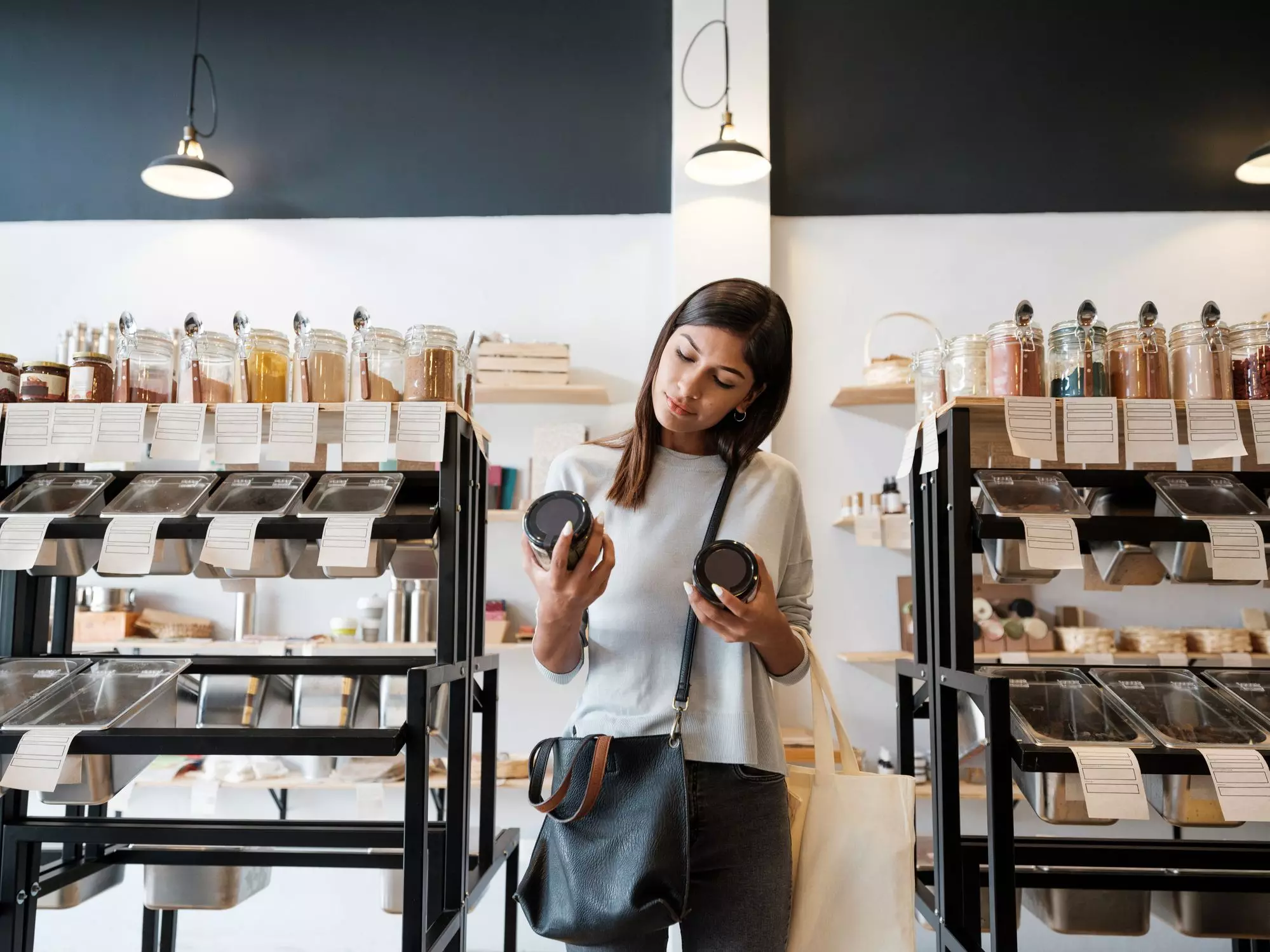 egy fiatal nő újrafelhasználható kannákat tart egy boltban