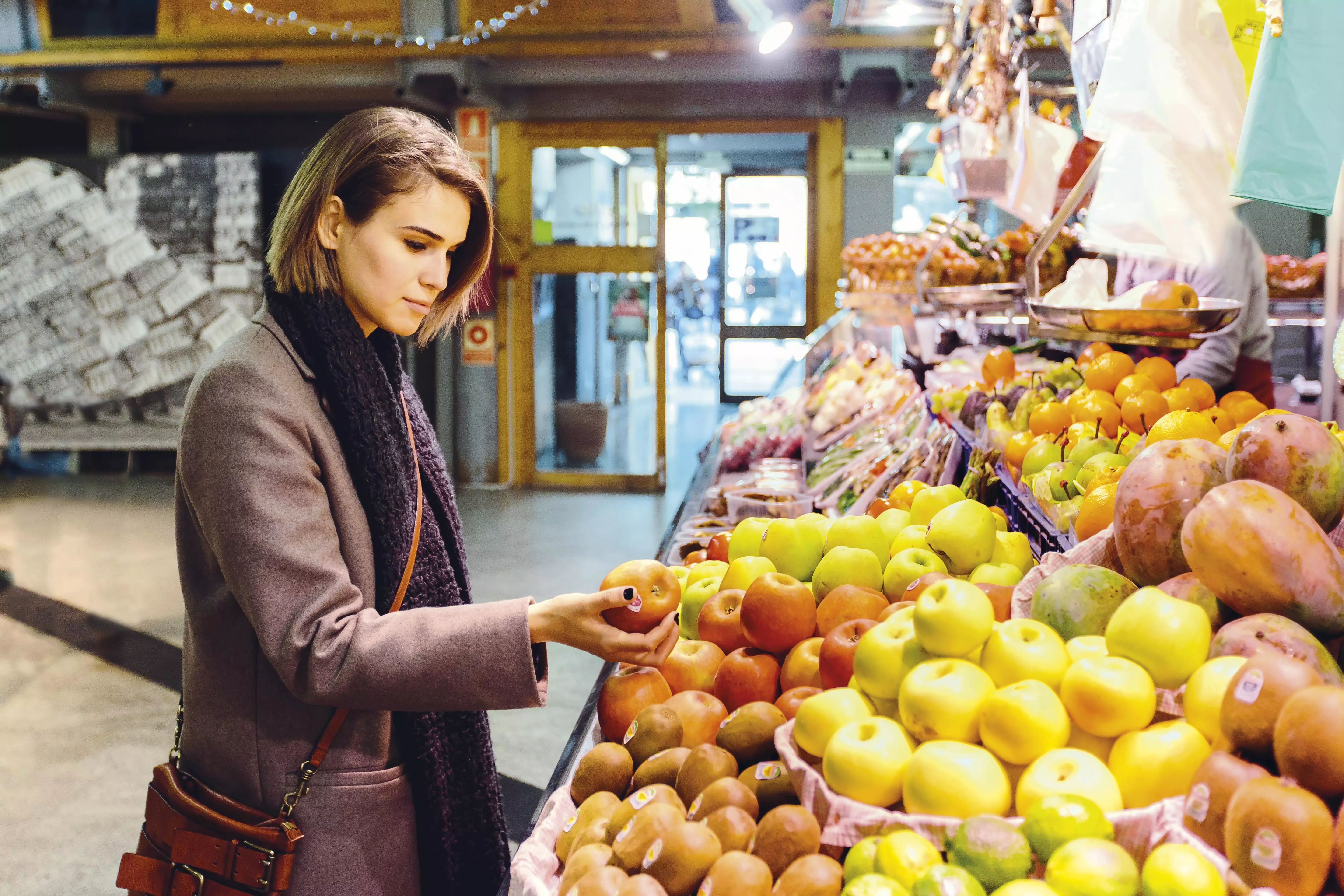 امرأة تشتري الفاكهة في السوبر ماركت