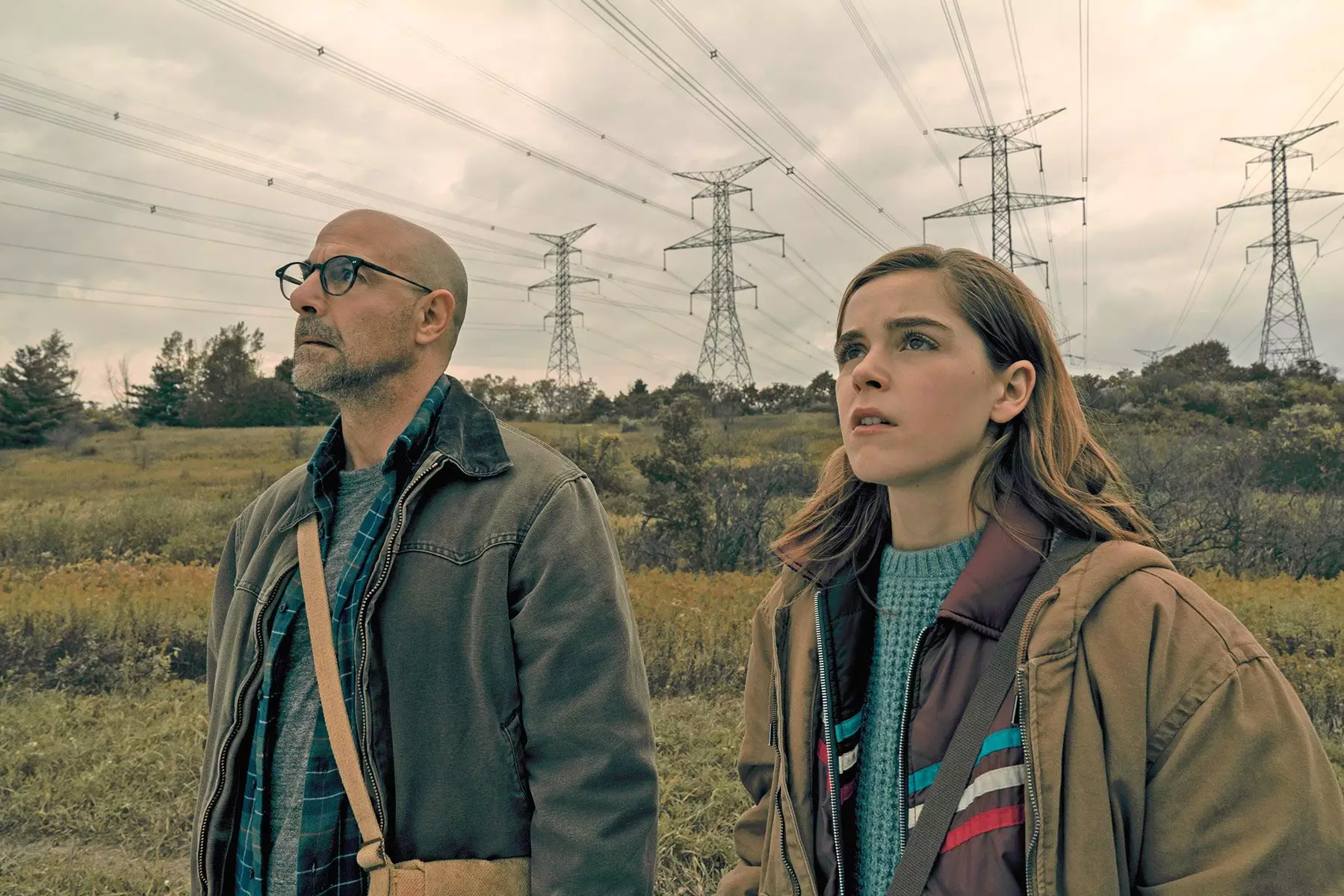 stanley tucci ja kiernan shipka katsovat ylös, niputettuna, keskellä peltoa, elokuvan kohtauksessa hiljaisuus