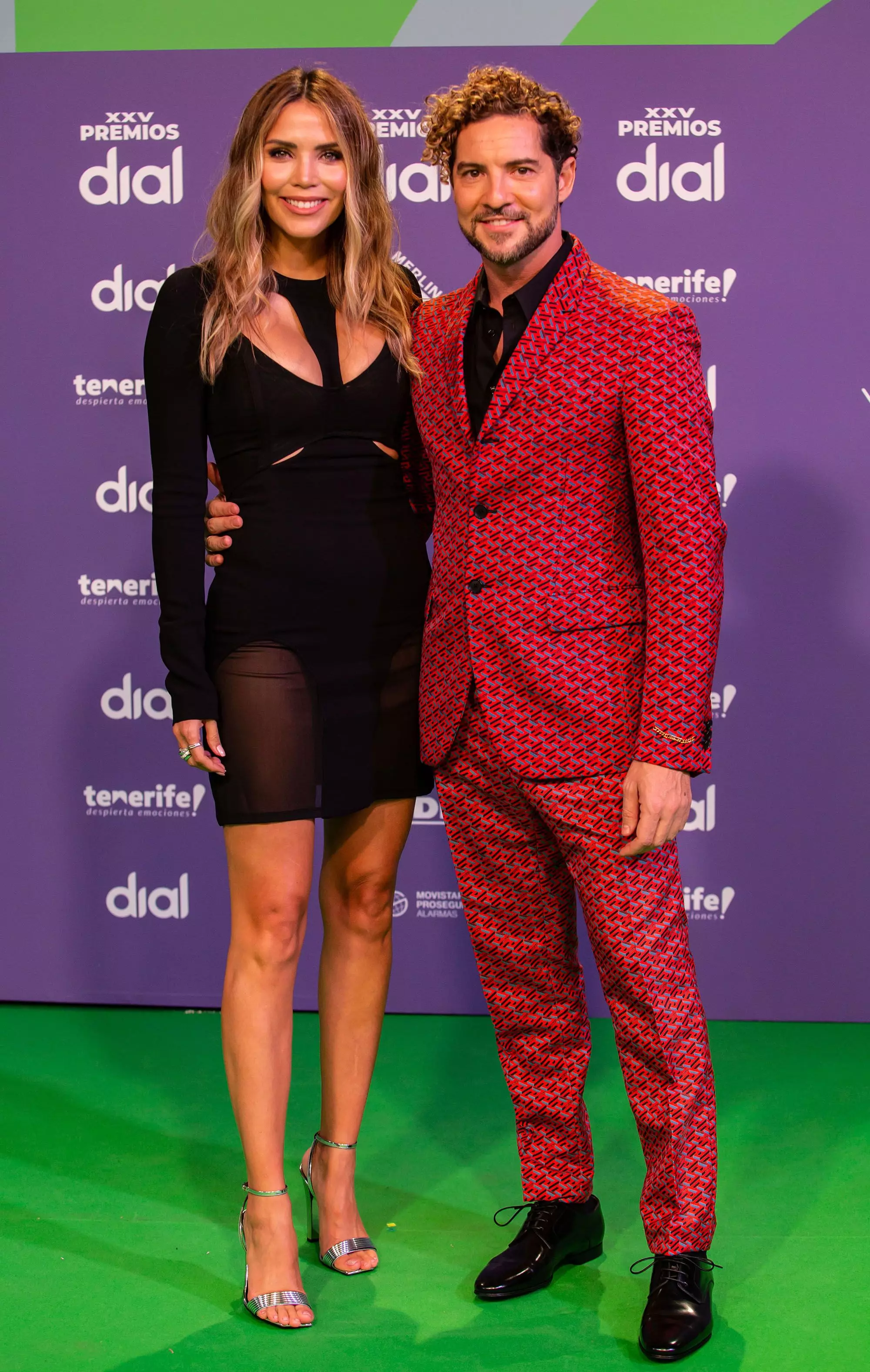 the singer and his wife pose embracing on the green carpet of these music awards