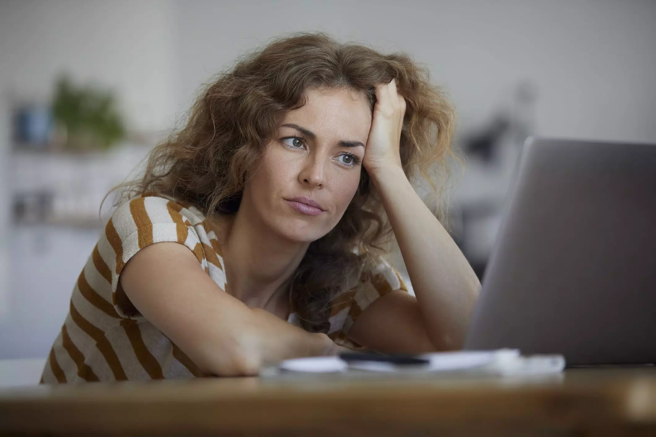 bir kadın, çok yorgun, dizüstü bilgisayar ekranına bakıyor