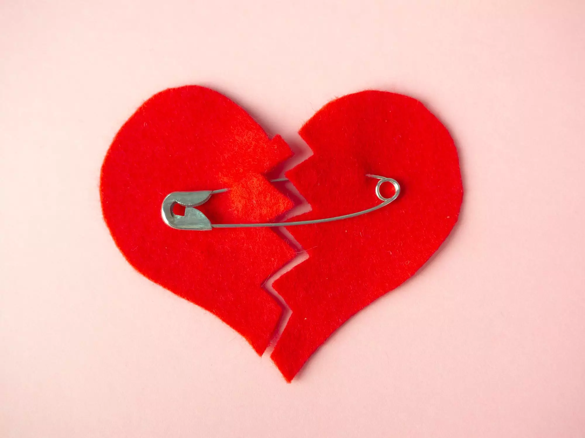 a red felt heart pieced together with a safety pin