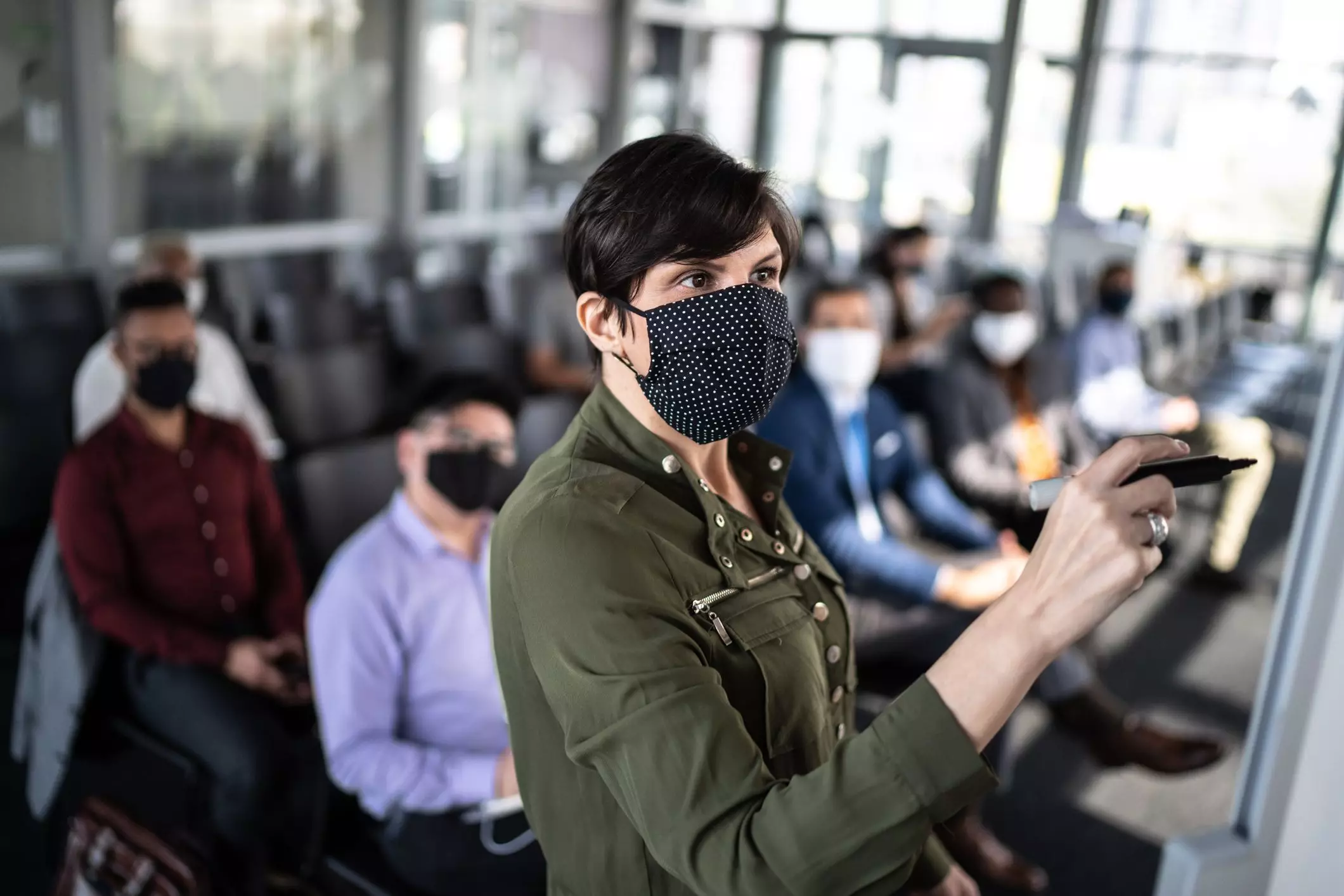 Mëttelalter Fra, déi eng Mask droen, schreift op engem Whiteboard mat engem Markéierer