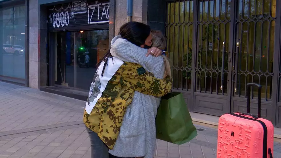 olga bru i rosada flors abraçades al carrer amb unes maletes