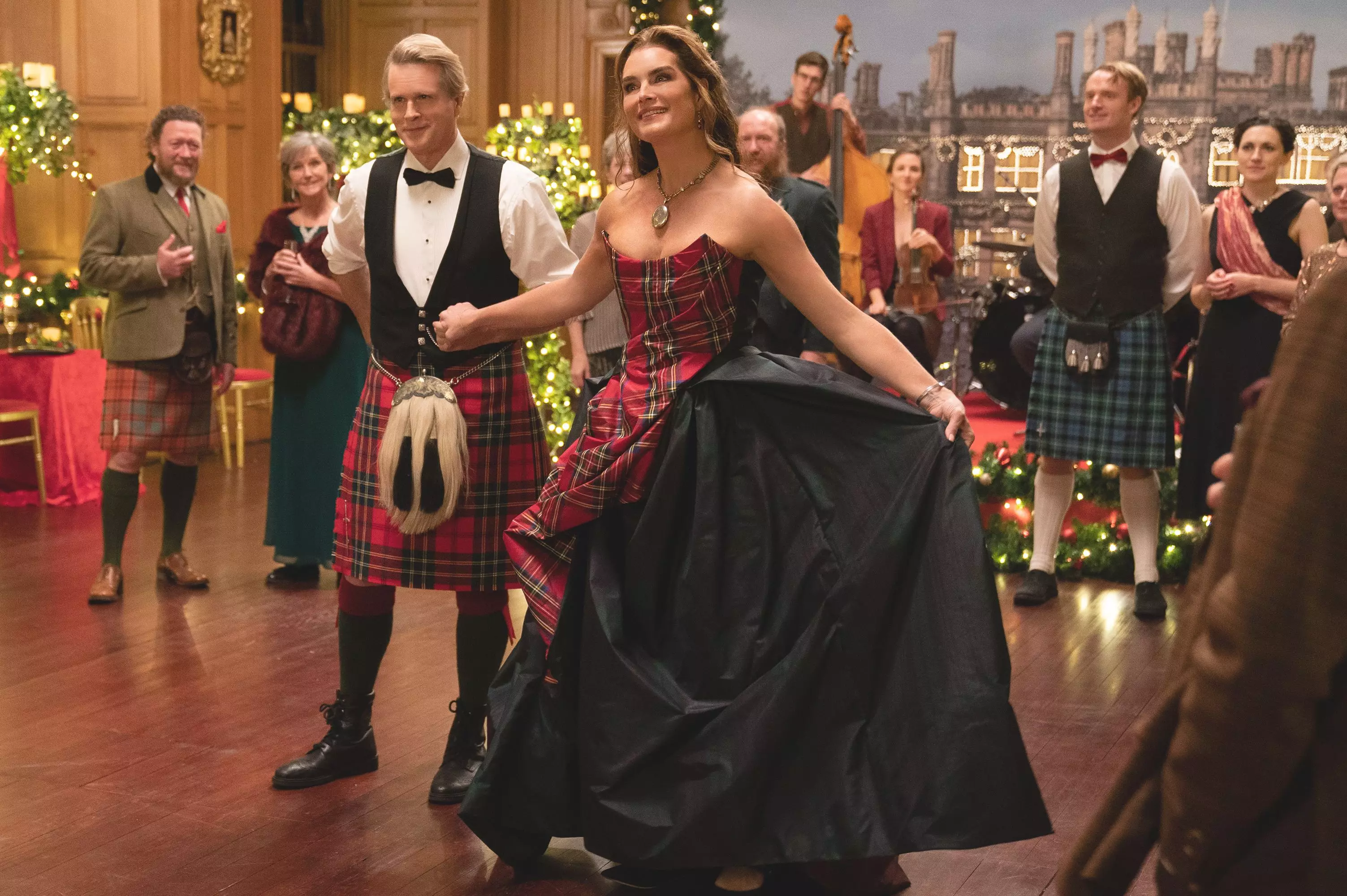 cary elwes i brooke shields, vestits amb vestits inspirats en el kilt escocès, ballen en un castell per Nadal