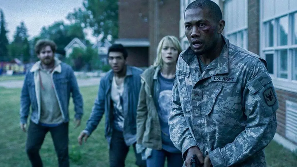 un grupo de catro persoas están armados camiñando por un céspede contra zombies
