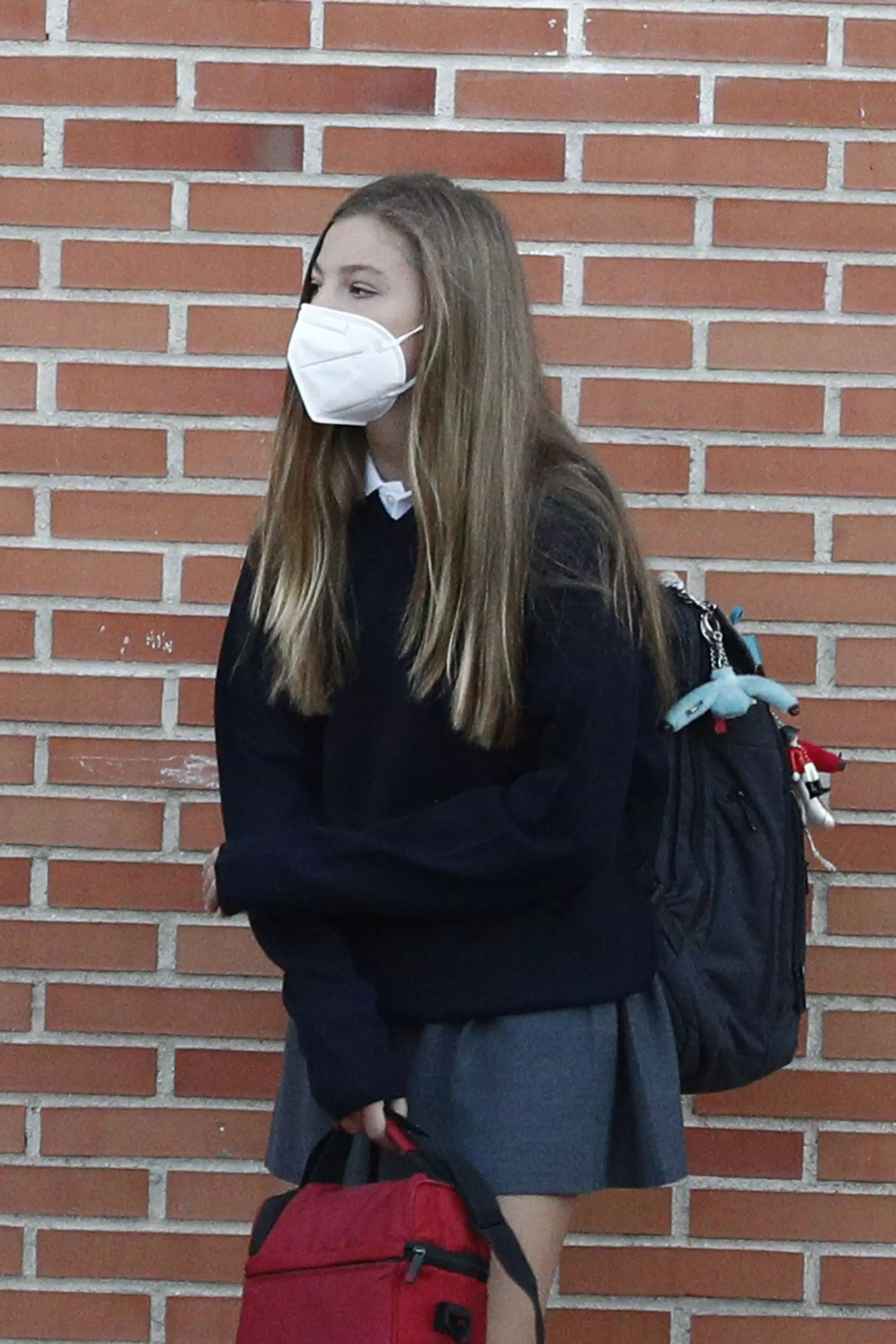 De jongste dochter van de koningen, met een masker en uniform, arriveert op haar school in Madrid