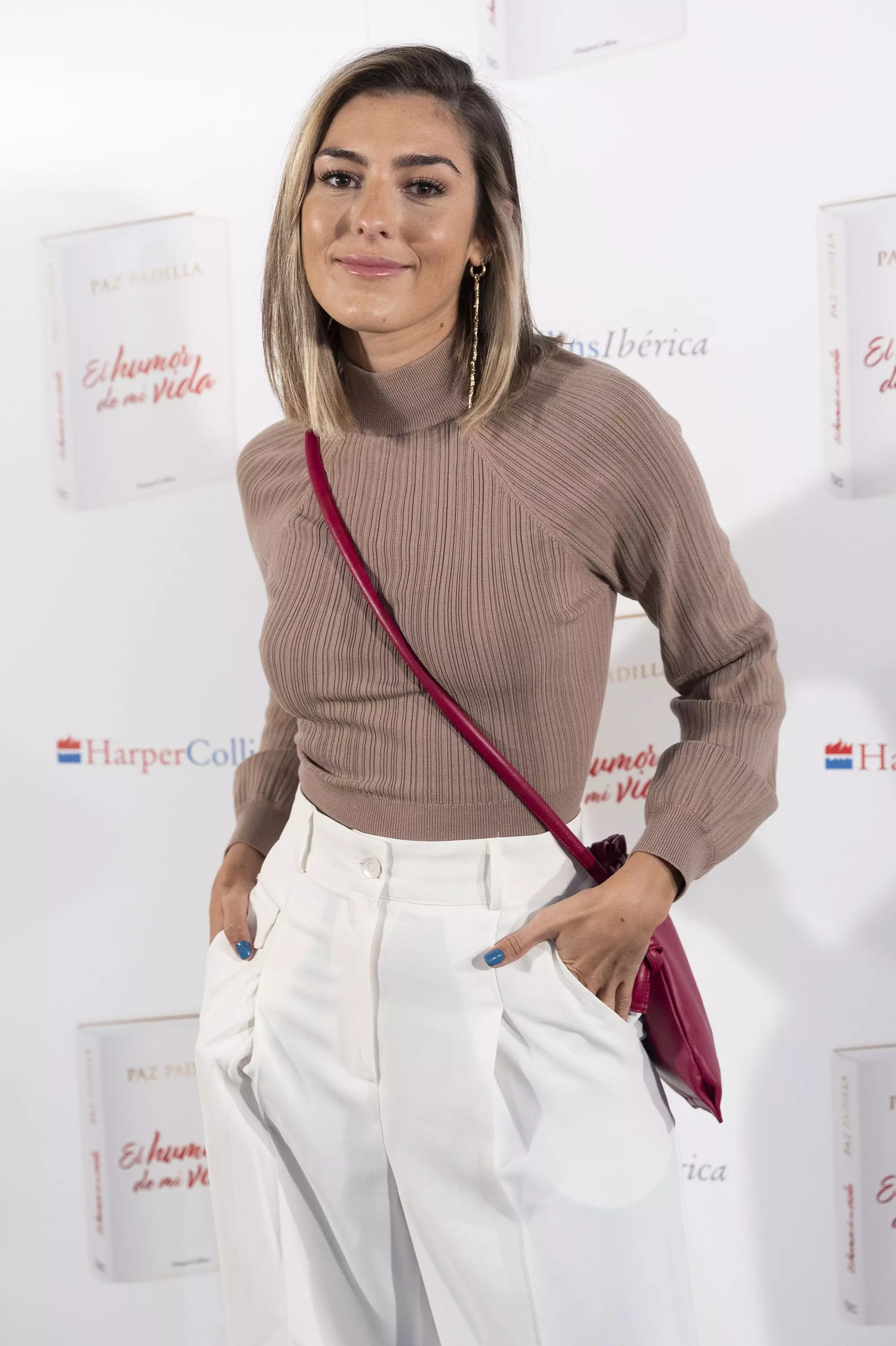 the daughter of paz padilla, with a brown turtleneck sweater, white pants and a bag from her nonina brand