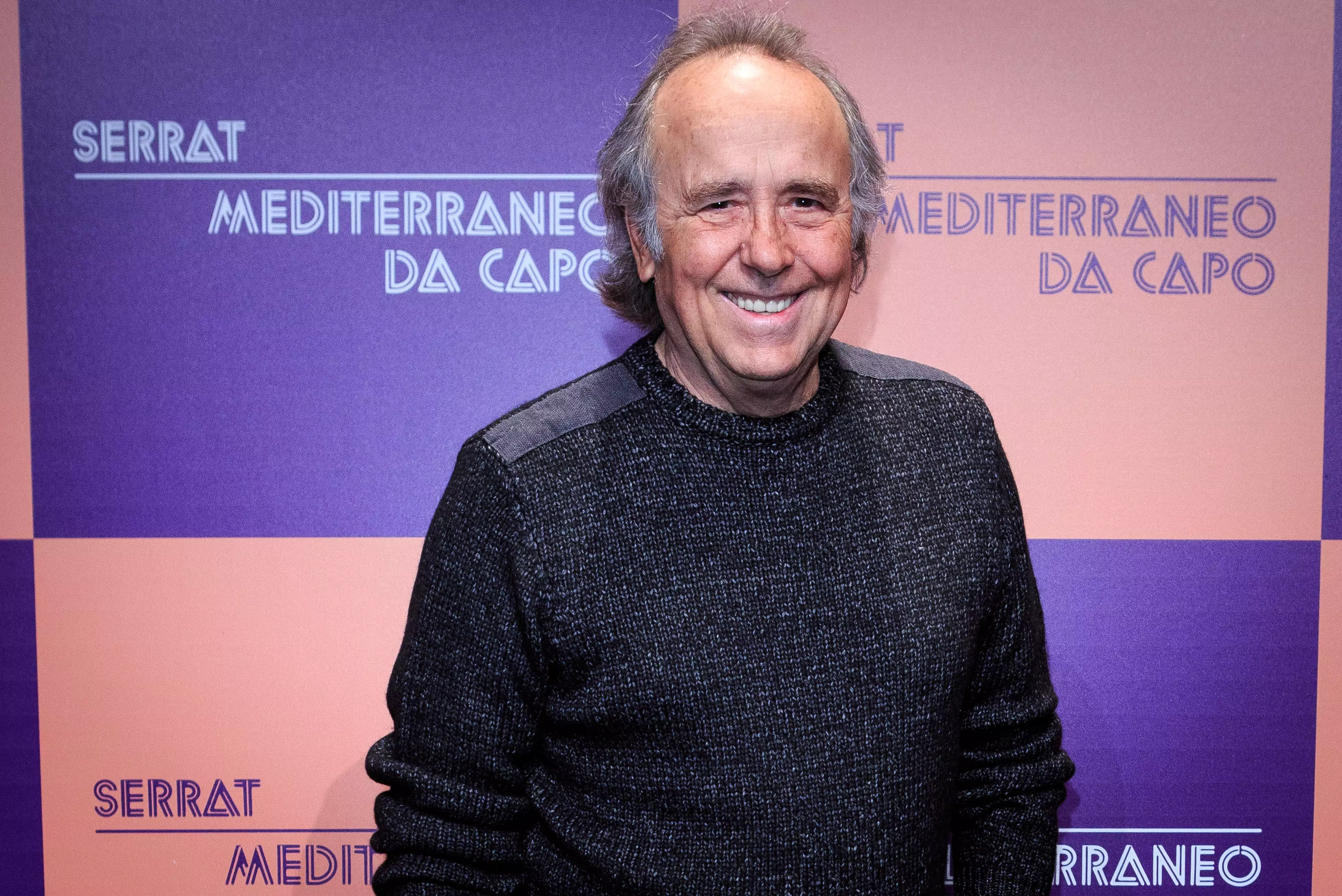 joan manuel serrat abeslaria photocall batean posatzen, eskuak poltsikoetan eta irribarrez