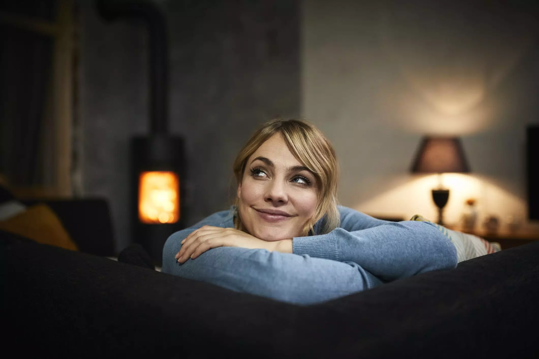 Portrait of smiling woman relaxing on couch at home in the evening