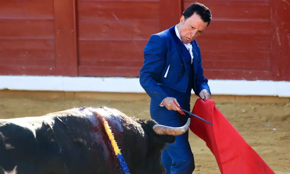 Ortega Cano lutando em um terno azul em uma praça de touros