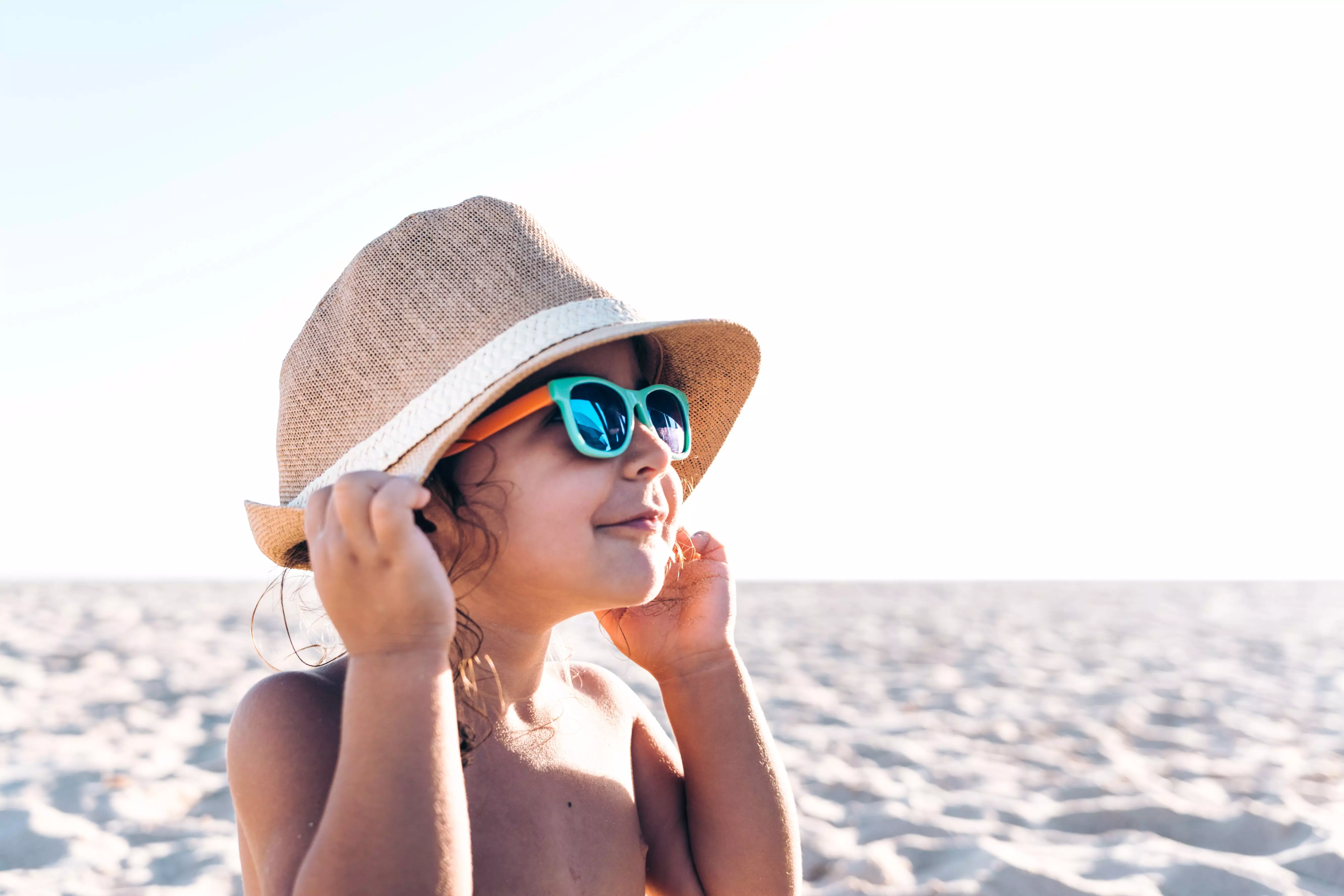 flicka på stranden med hatt och glasögon