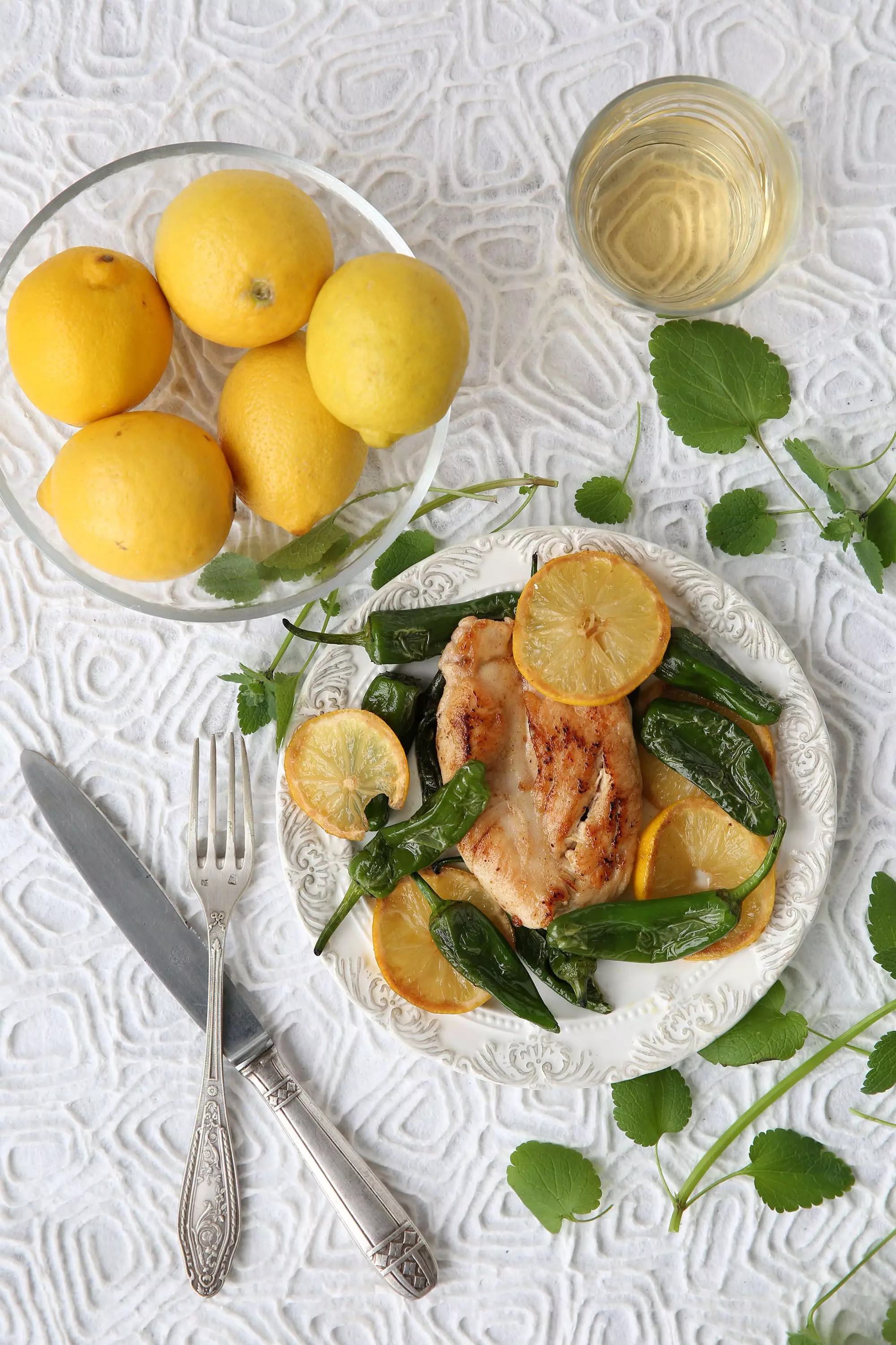 un bol de citrons à côté d'une assiette de poulet, citrons et poivrons