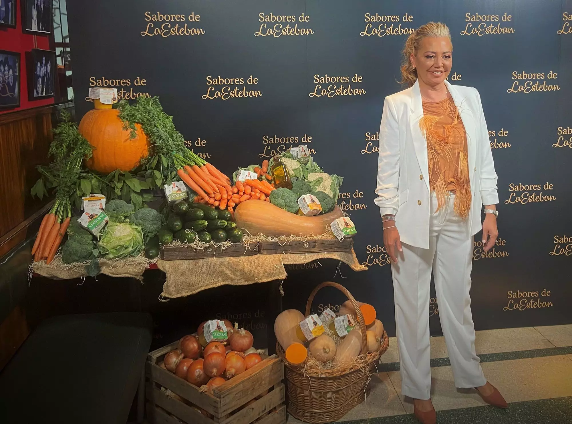 the collaborator in a white suit next to her new products and a still life of vegetables