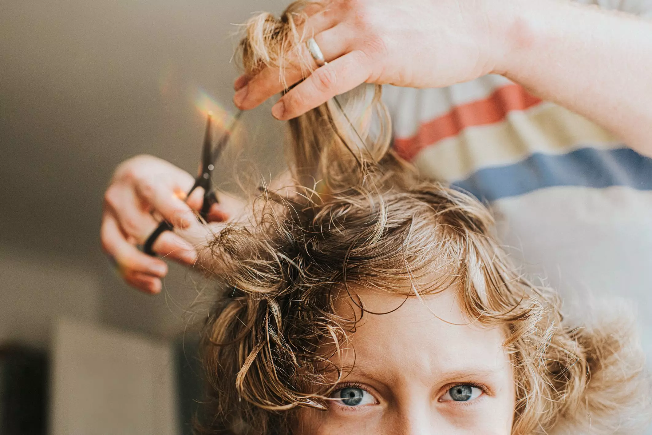 lalaki nga nagputol sa buhok sa batang lalaki nga adunay kulot nga buhok