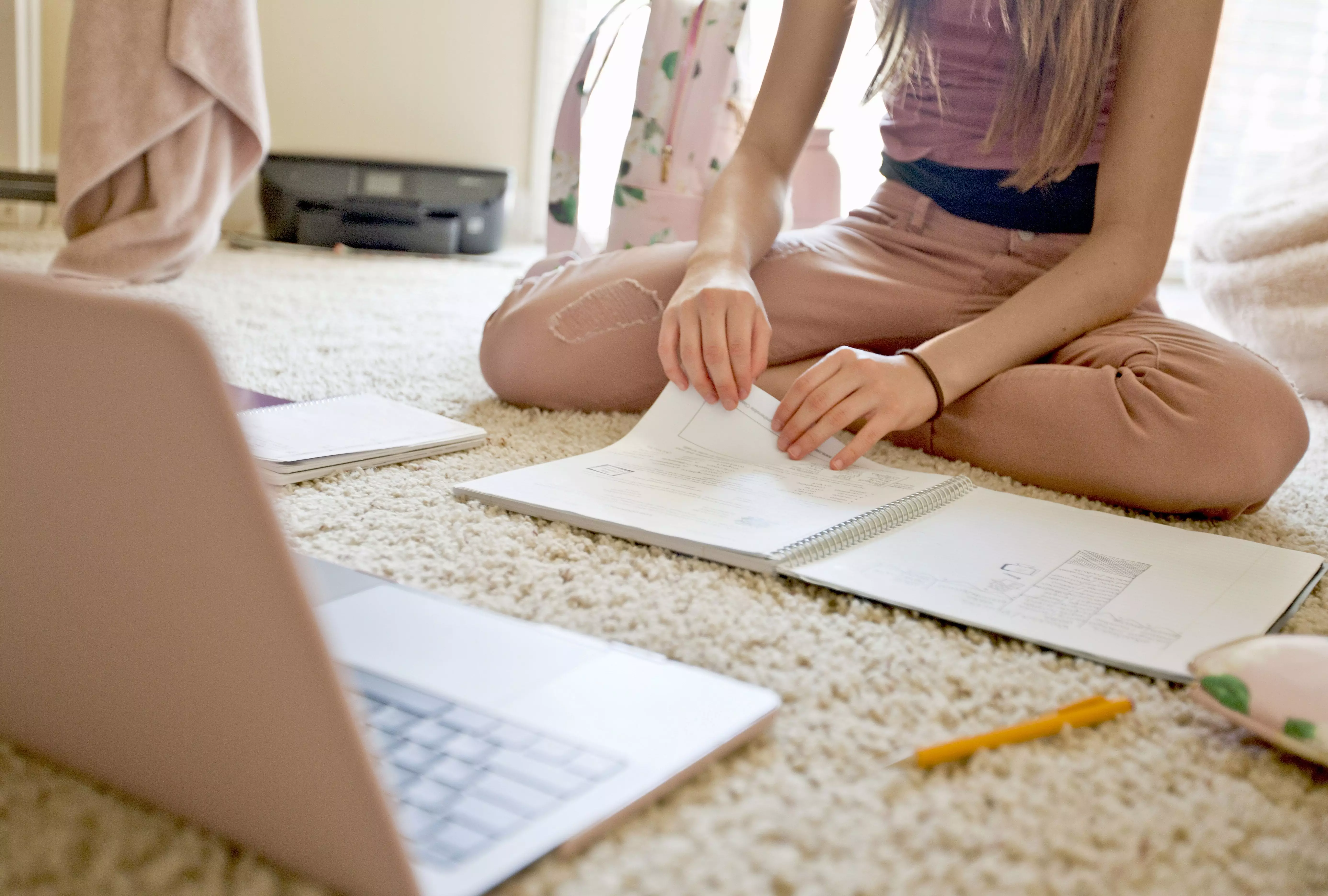 コンピューターを持つ 10 代の少女が自分の部屋で宿題をする