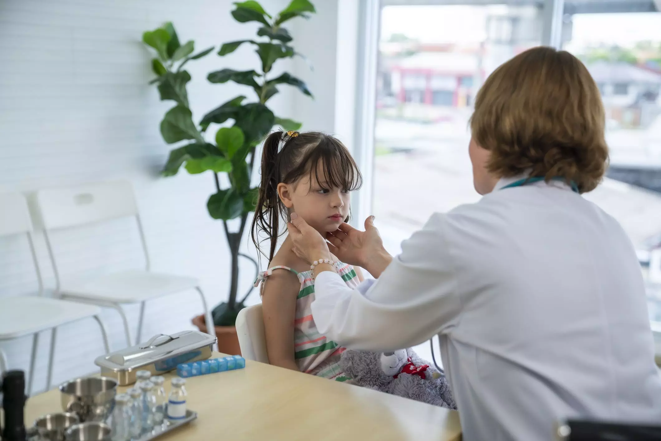 kvinnelig lege sjekker liten jentes hals på sykehus