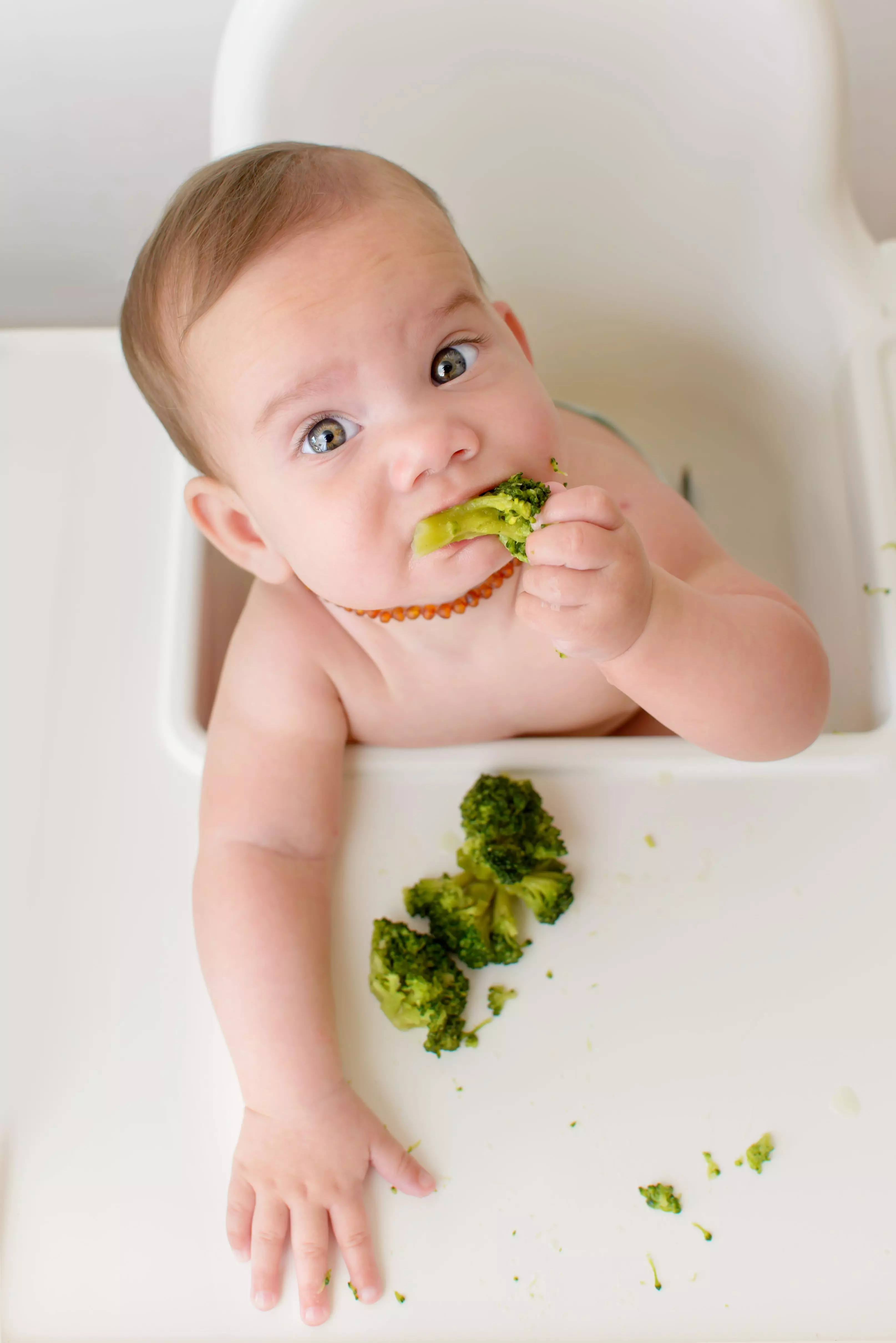 dojenček je brokoli v stolčku za hranjenje
