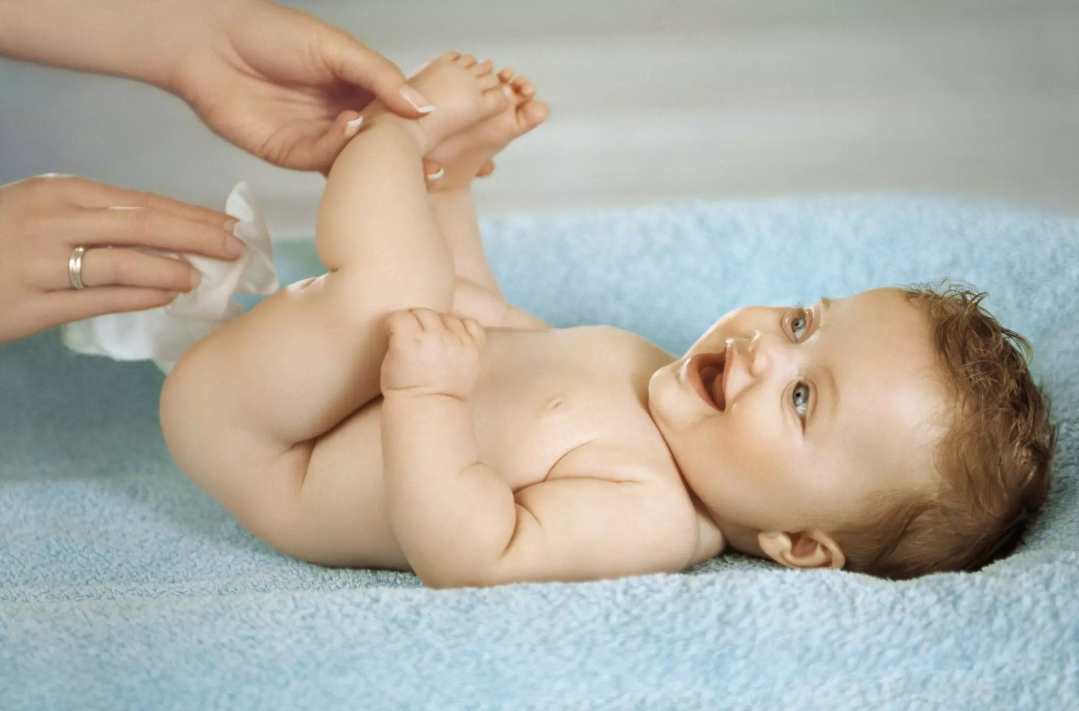 mother wiping the baby's bottom with a wipe