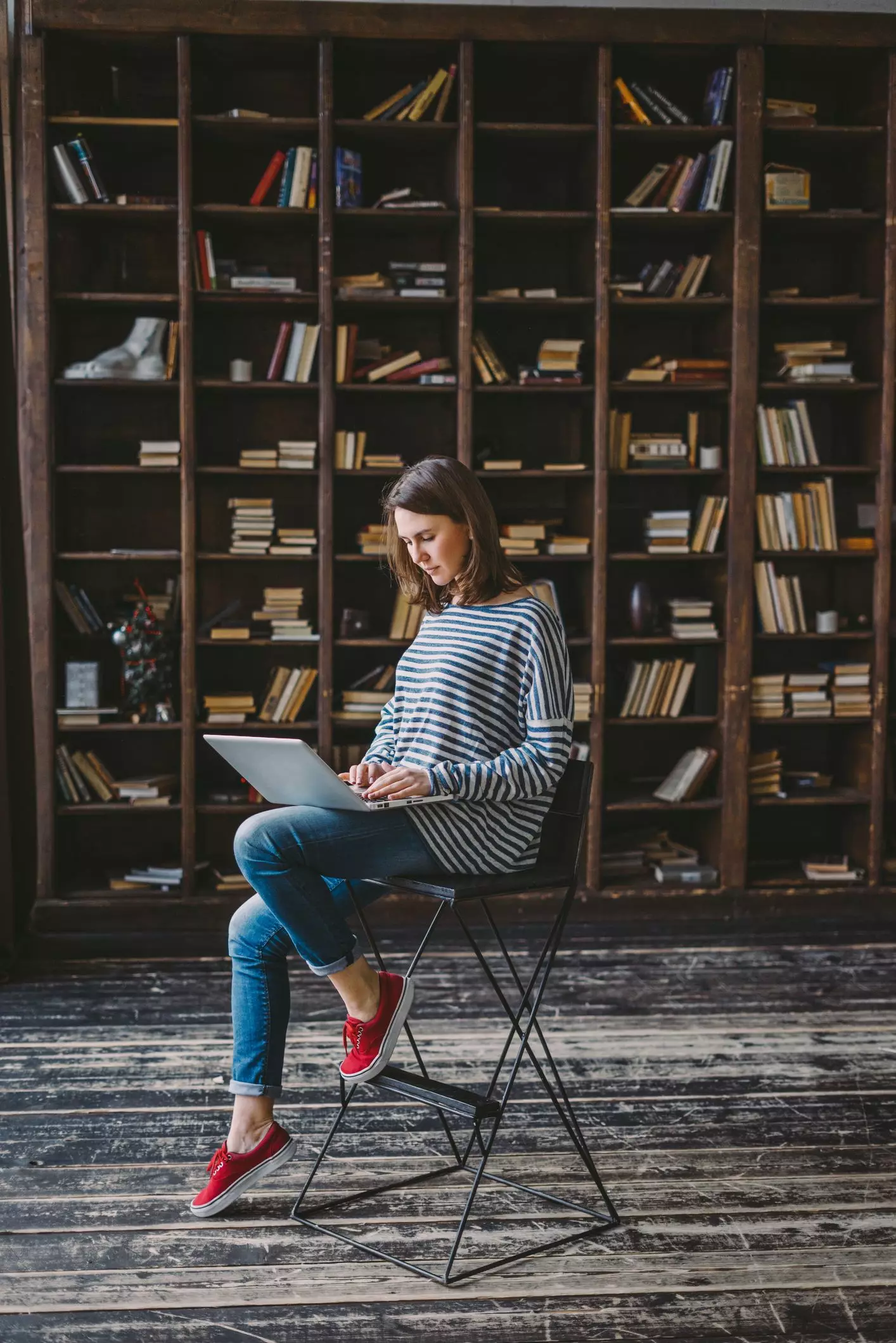 mulher digitando em um computador em frente a uma grande biblioteca