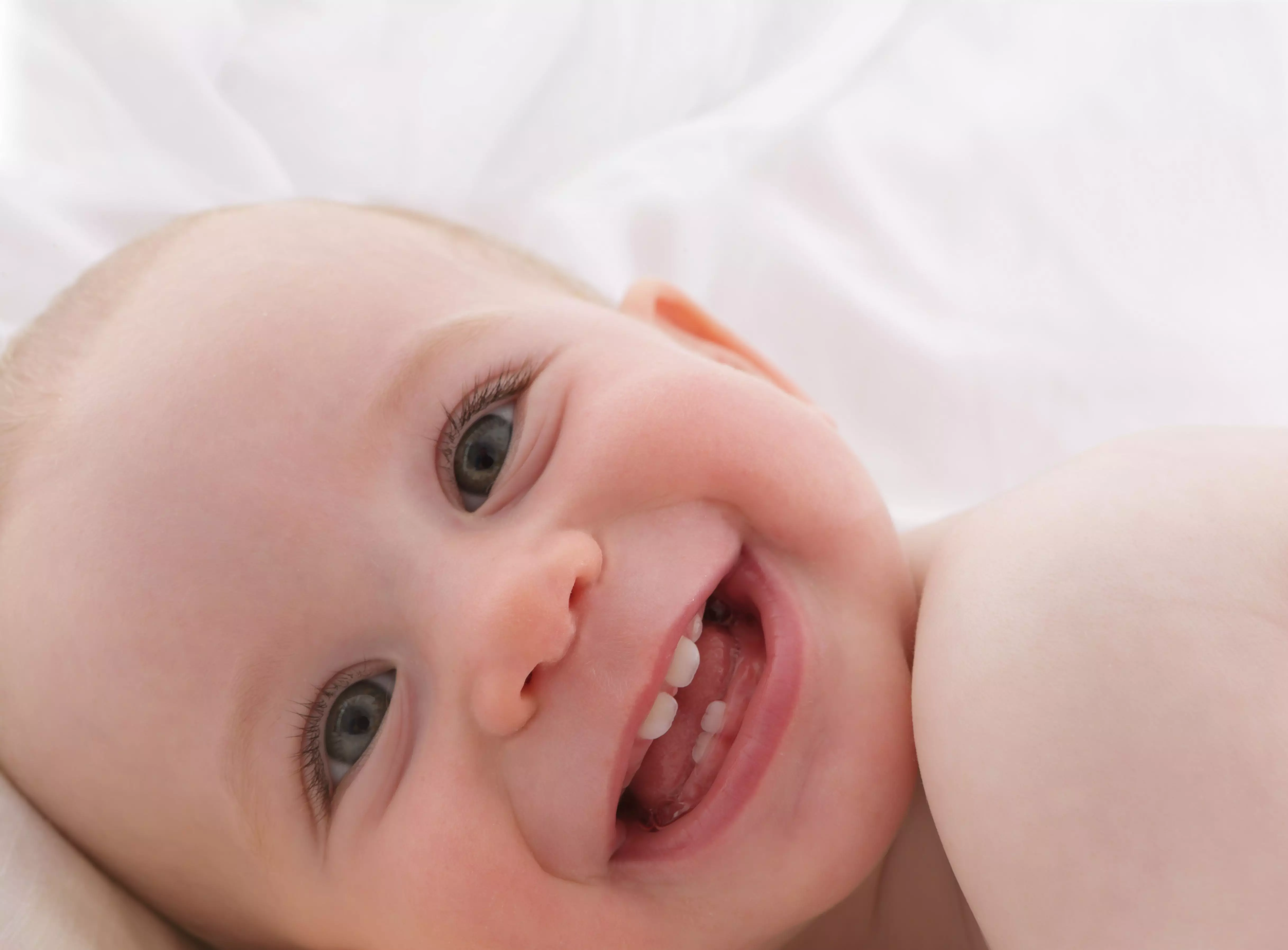 bebê feliz mostrando seus primeiros dentes de leite