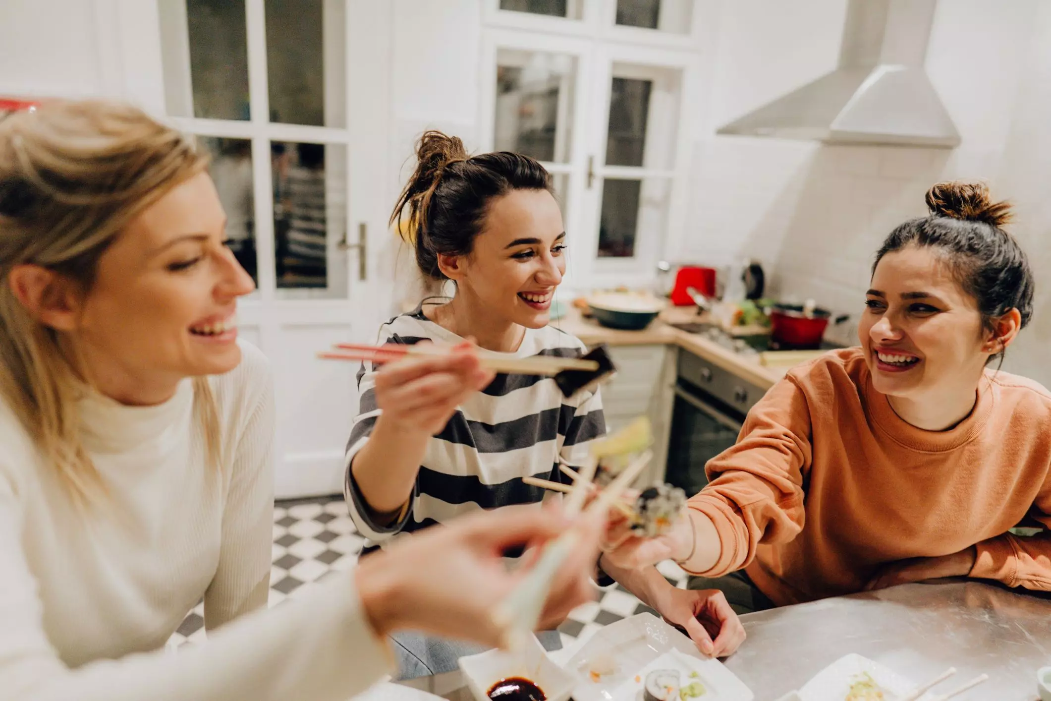 några tjejer njuter av en middag med vänner och äter sushi