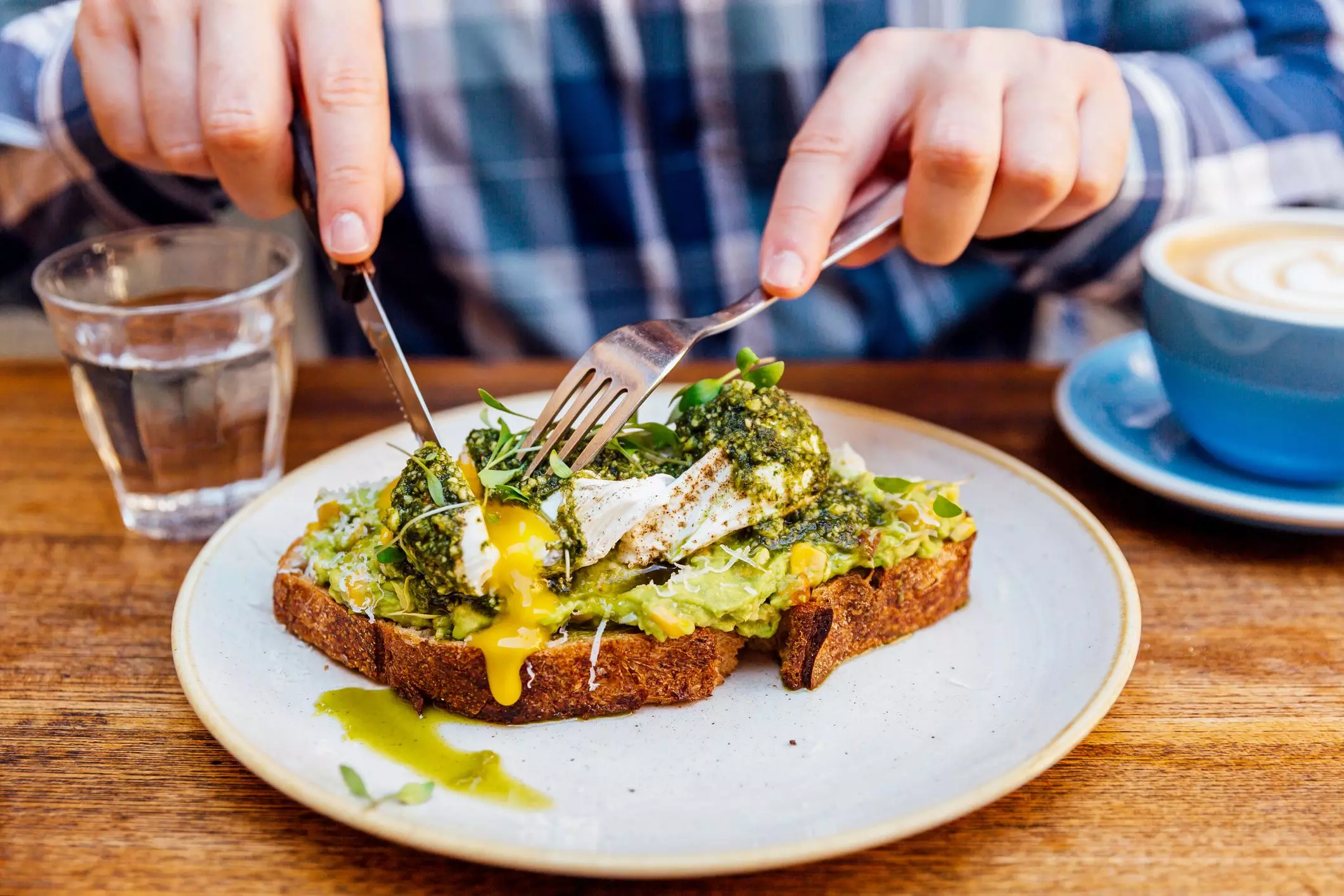 man eet avokado-roosterbrood met geposjeerde eier, naby